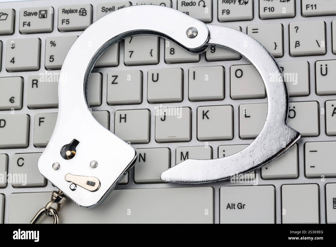 Handcuffs lie on the keyboard of a computer. Symbolic photo for ...