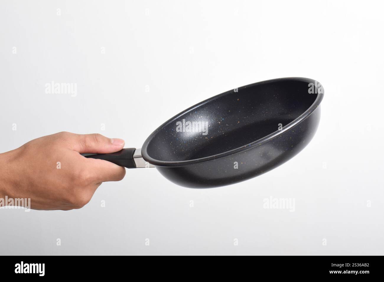 Hand holding Black frying pan with a non-stick coating isolated on ...