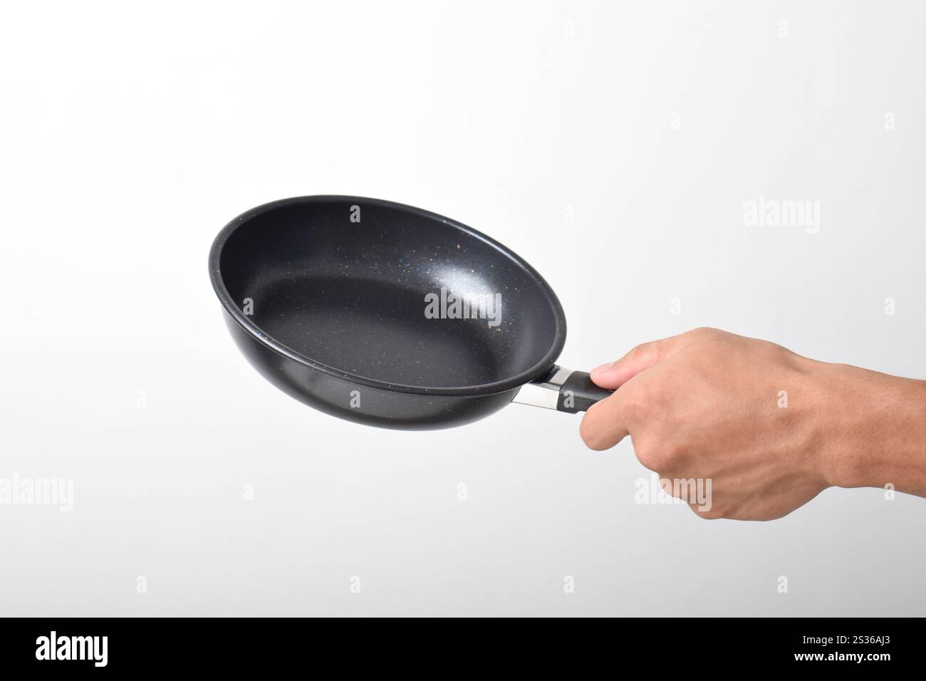Hand holding Black frying pan with a non-stick coating isolated on ...