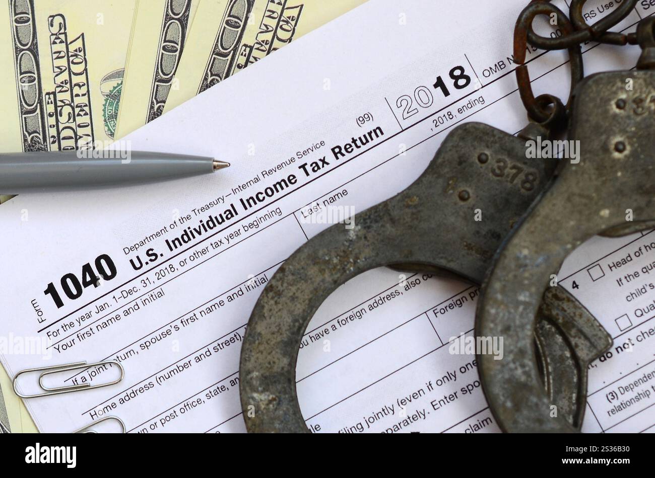 Police handcuffs lie on the tax form 1040. The concept of problems with ...