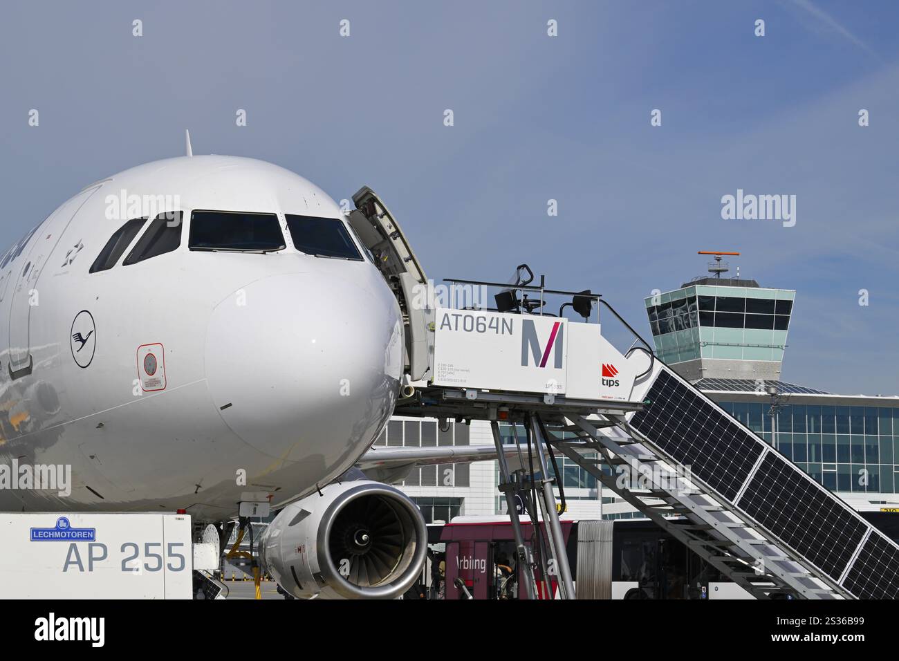 Lufthansa Airbus aircraft at check-in position with solar passenger stairs, power generator, bus ...