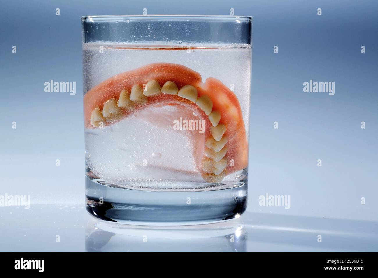 A dental prosthesis is cleaned in a glass of water. Proper hygiene ...