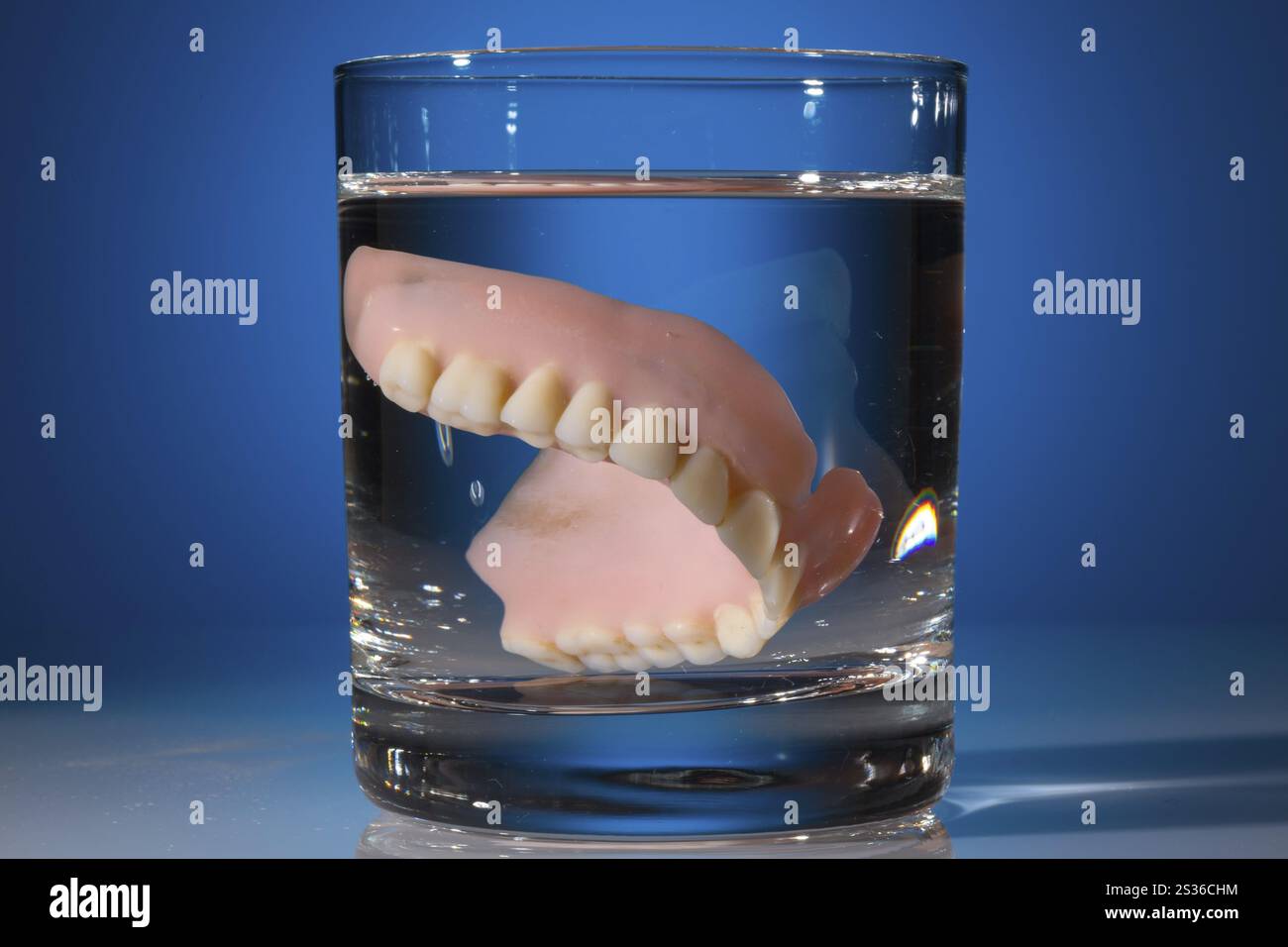 A dental prosthesis is cleaned in a glass of water. Proper hygiene ...