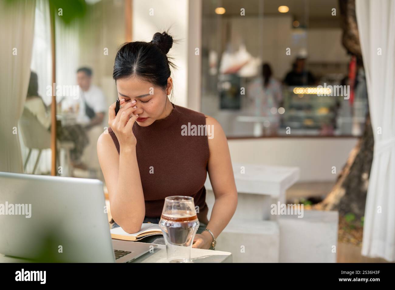 A frustrated Asian woman feels stressed and headache while working ...