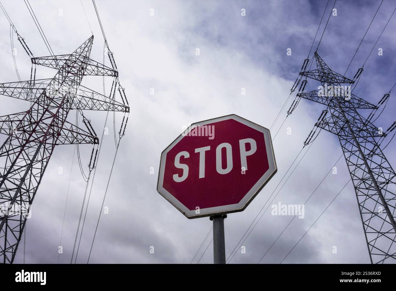 A pylon of a power line and a stop sign. Symbolic photo in favour of ...