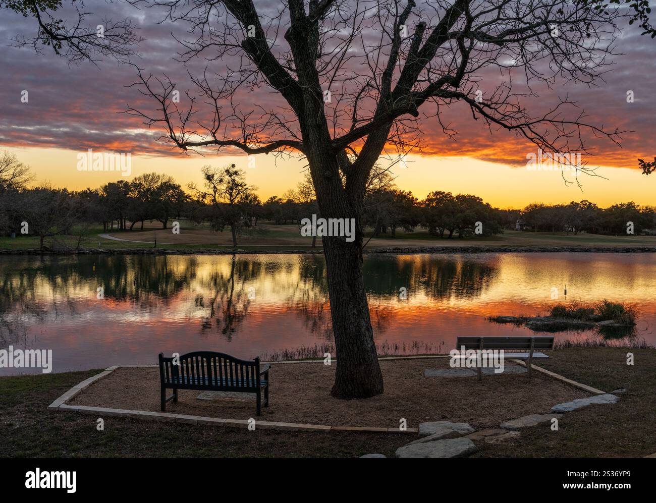 Dramatic sunset lighting a layer of clouds and reflected in the still ...