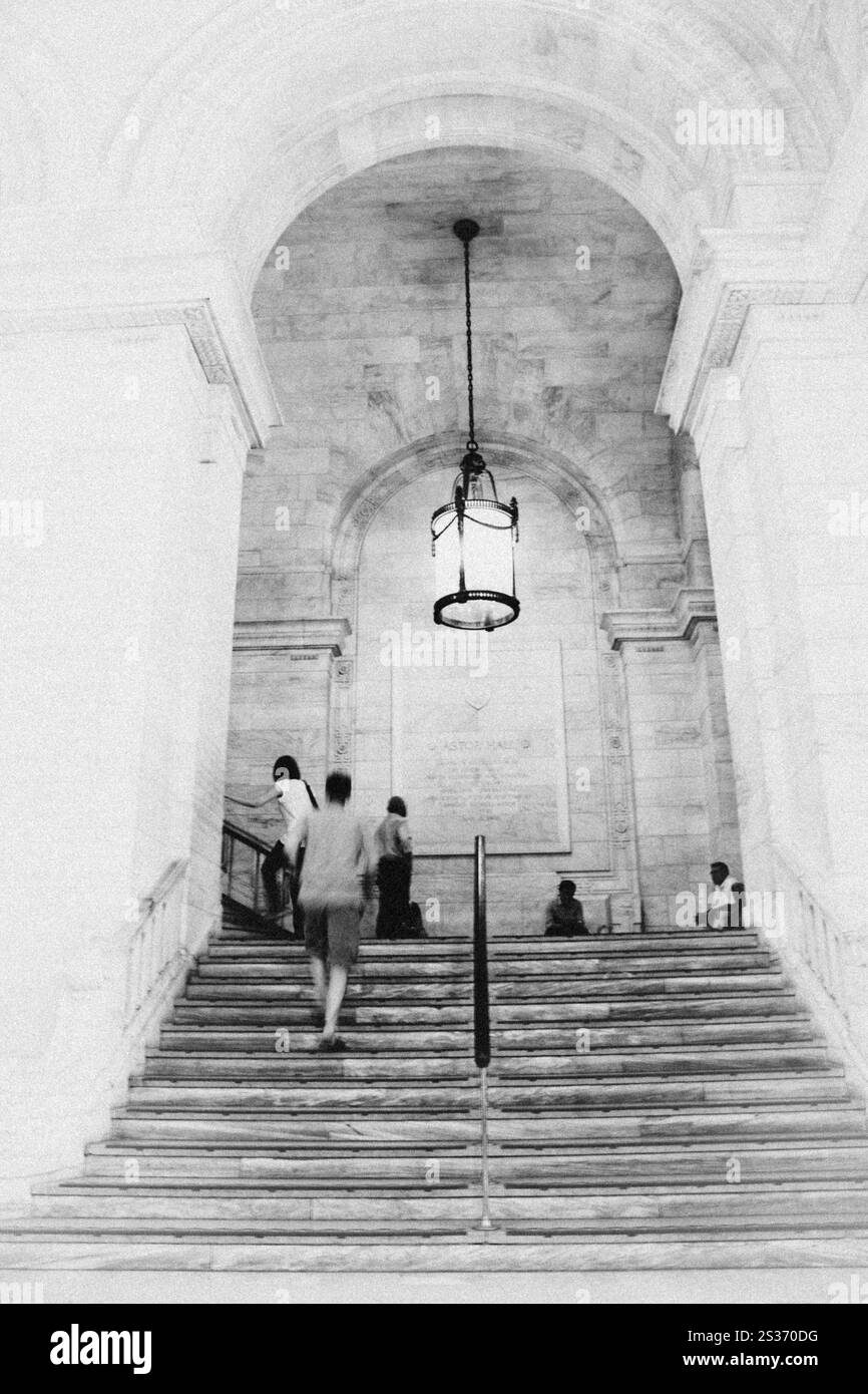 Man walking up stairs in library Stock Photo - Alamy