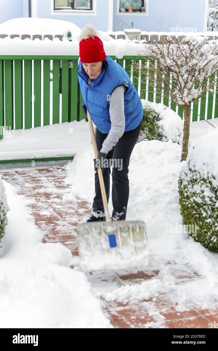 A woman shovels the new snow from a path. Onset of winter in Austria ...