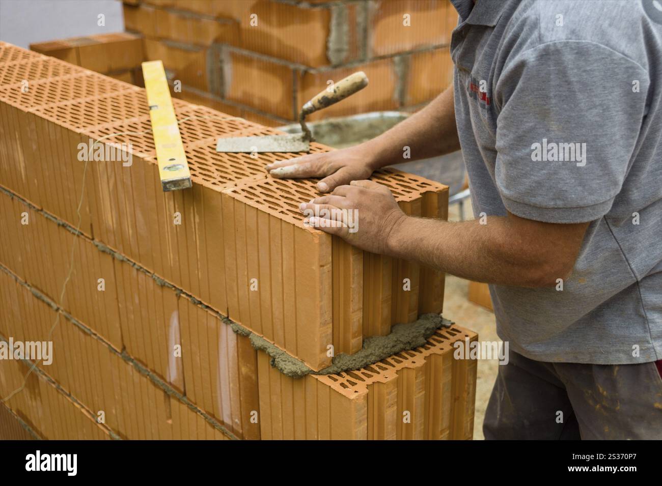 Anonymous construction worker on a building site erecting a brick wall ...