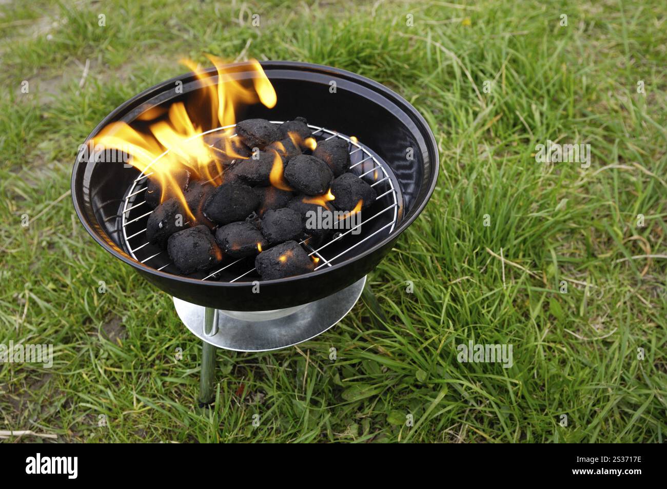 Charcoal briquettes burning in a small portable barbeque standing on ...