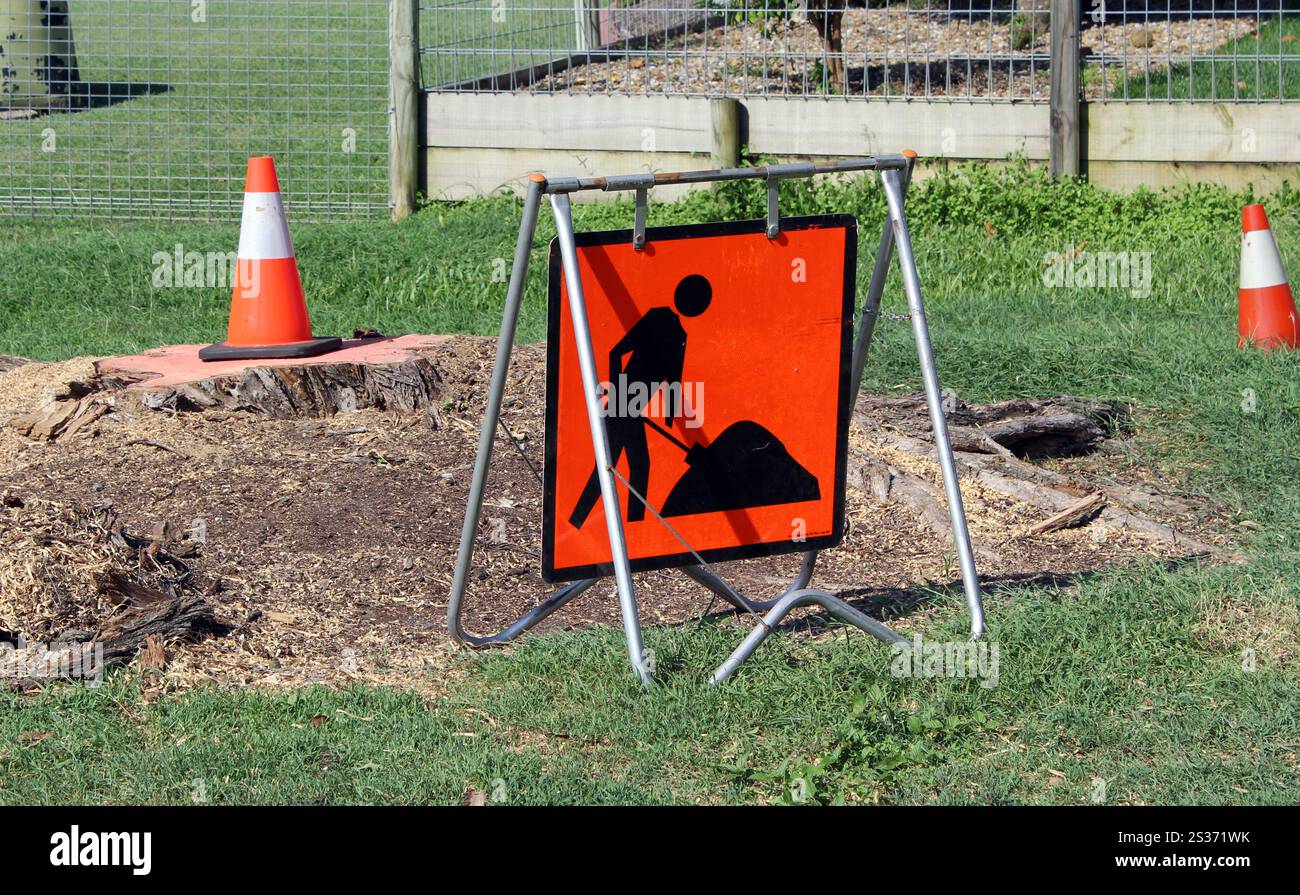 Workmen Ahead warning sign with orange cones and a tree stump in the ...