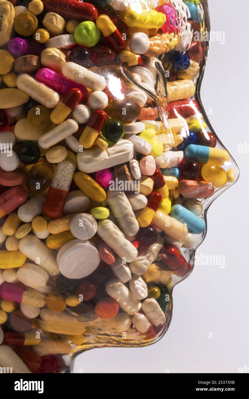 A glass head filled with many tablets. Symbolic photo for medication ...