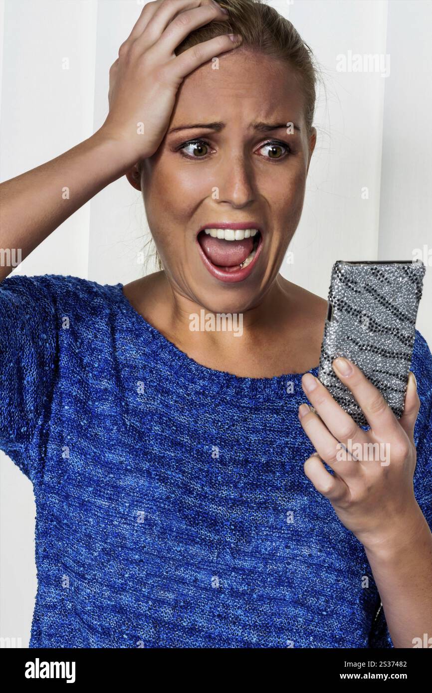 A woman receives bad news by text message and is shocked. Austria Stock ...