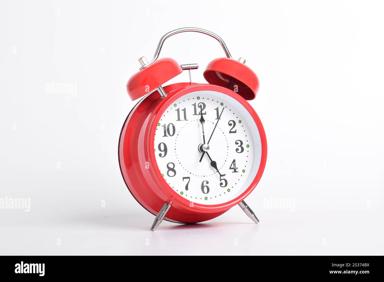 Red alarm clock set at five o'clock isolated on white background. Close ...