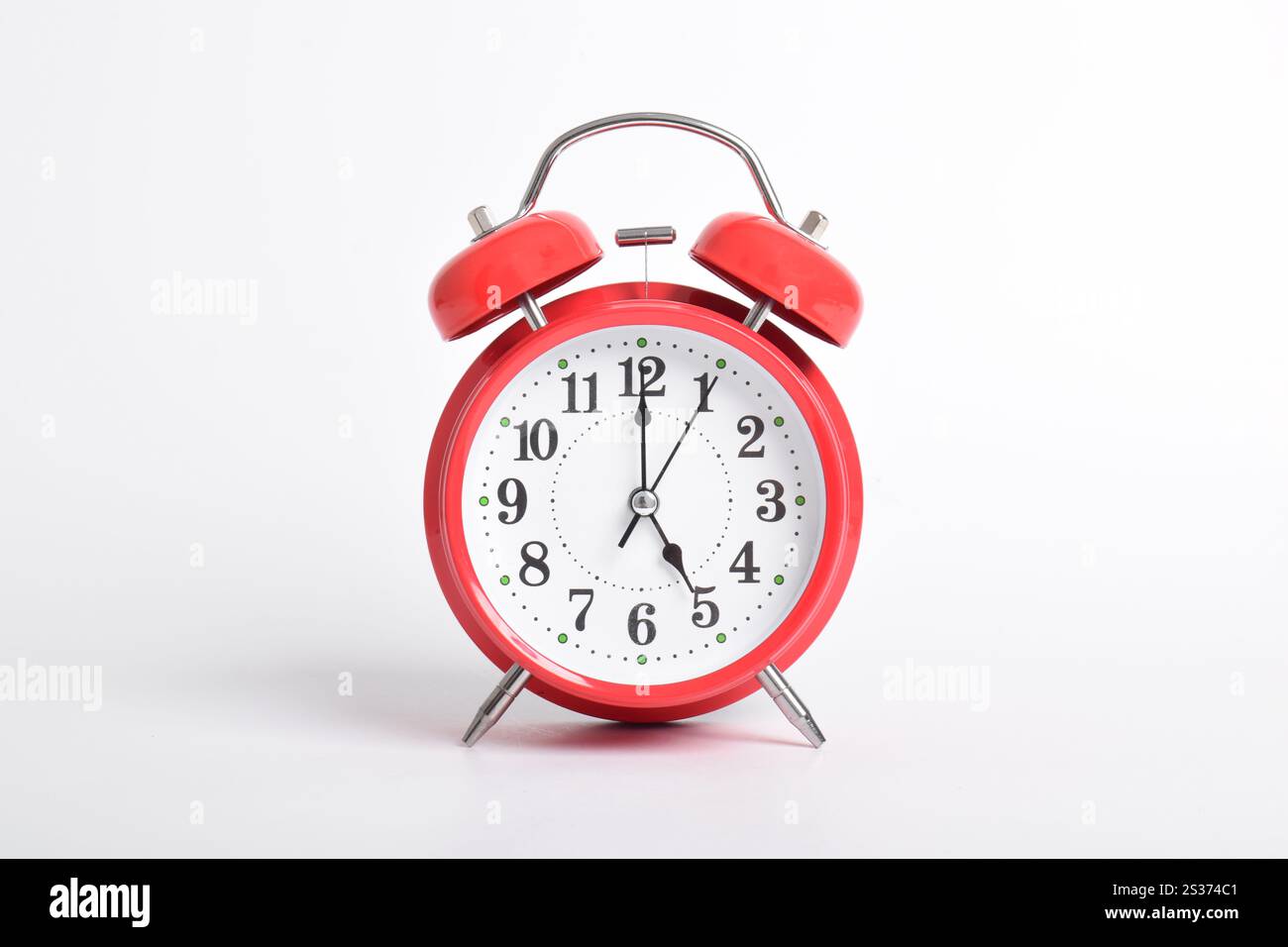 Red alarm clock set at five o'clock isolated on white background. Close ...