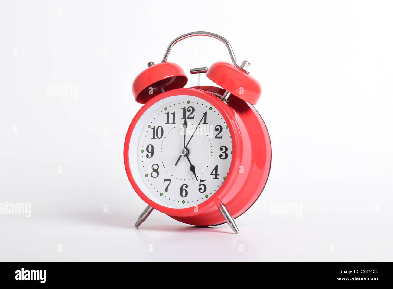 Red alarm clock set at five o'clock isolated on white background. Close ...