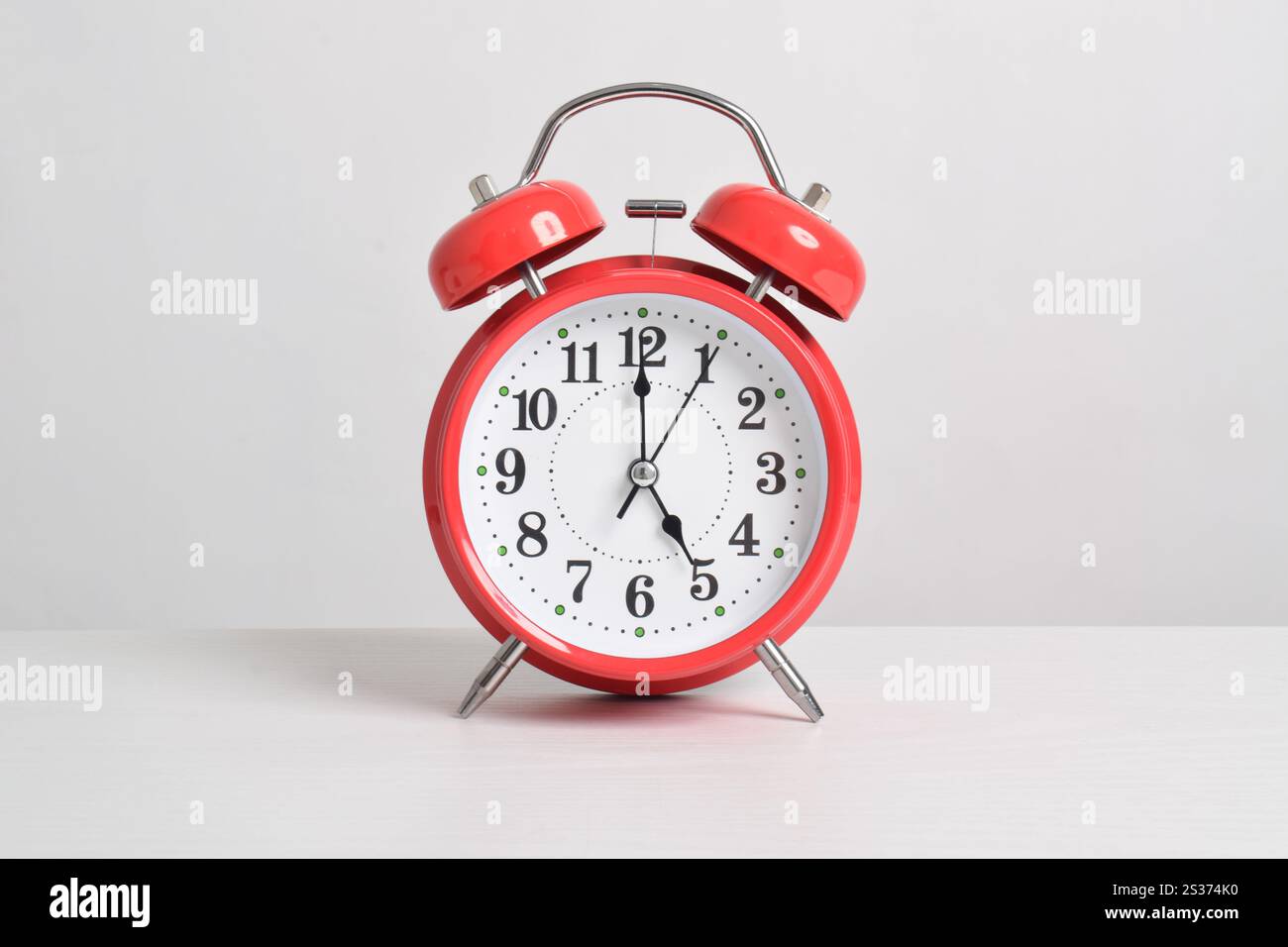 Red alarm clock set at five o'clock on table isolated on white ...