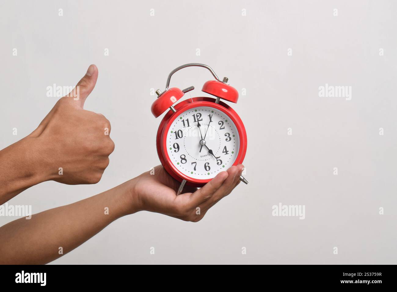 Hand holding alarm clock and giving thumbs up. Man holding red alarm ...