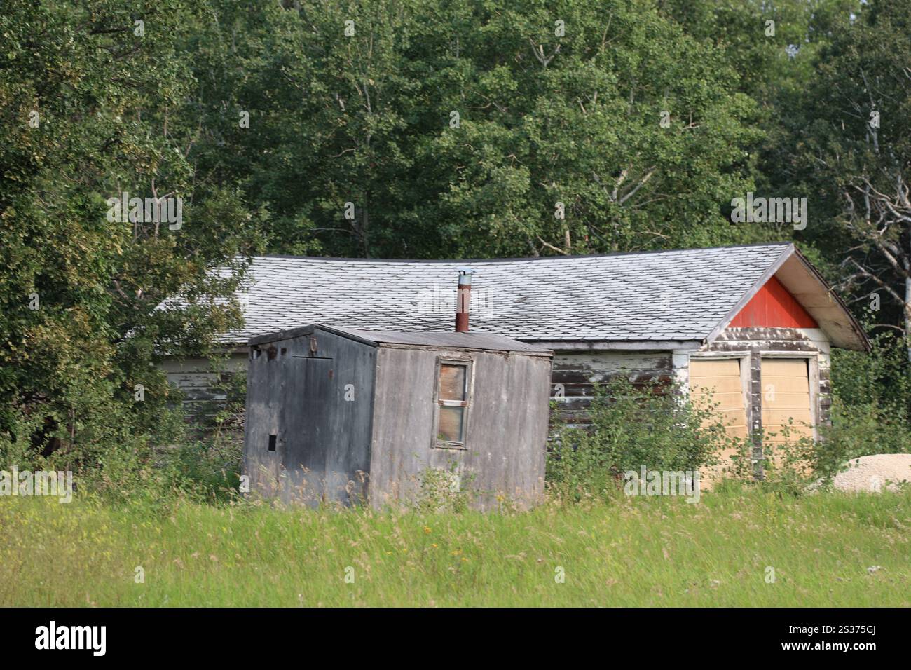 small dilapidated wooden shed with rusting chimney against derelict ...