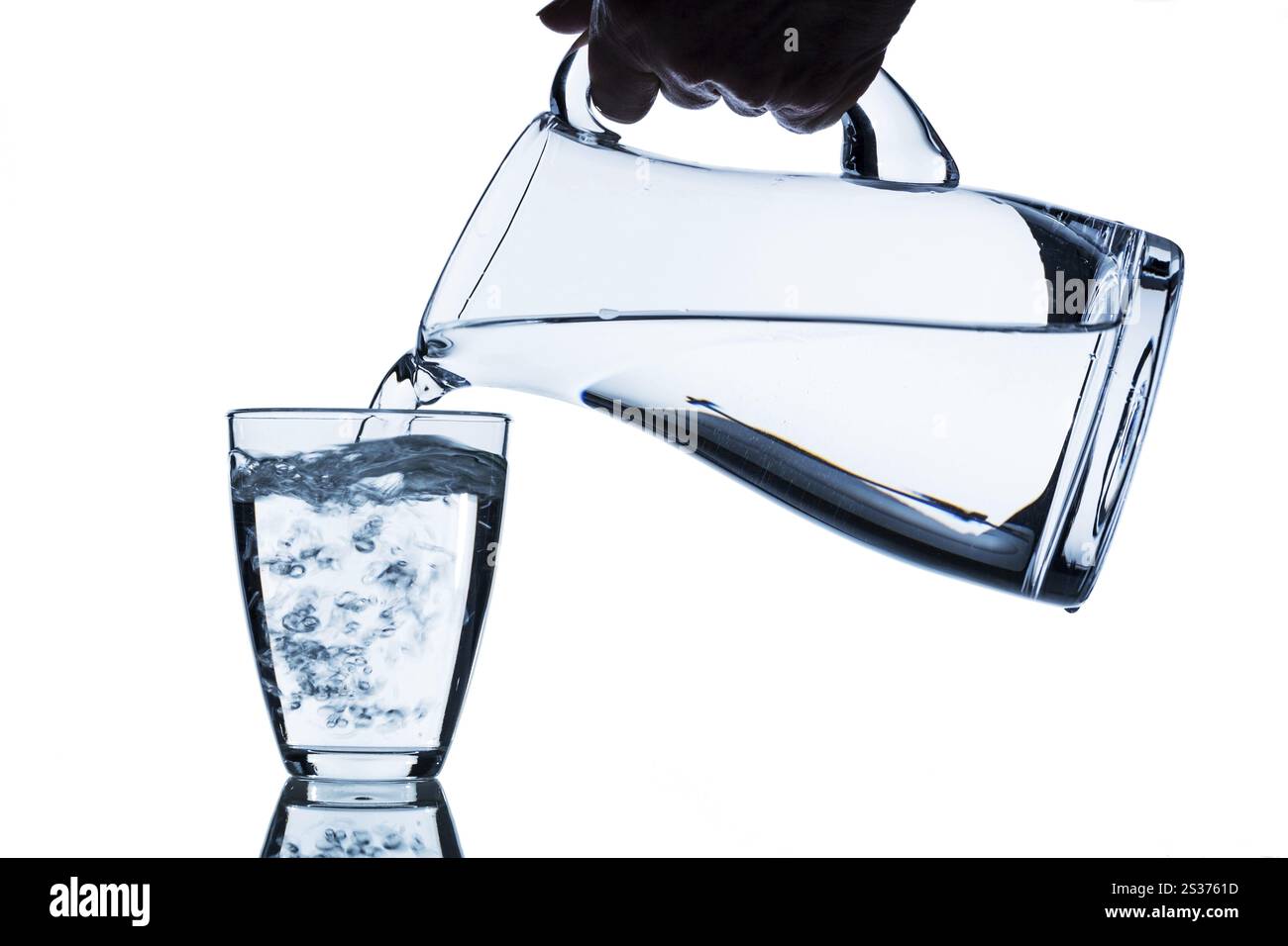 Pure water is poured into a water glass from a jug. Fresh drinking ...