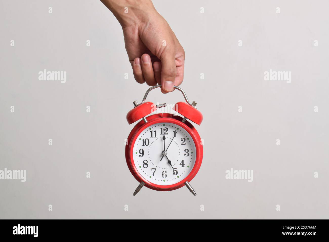Man holding red alarm clock in hand isolated on white background. Close ...