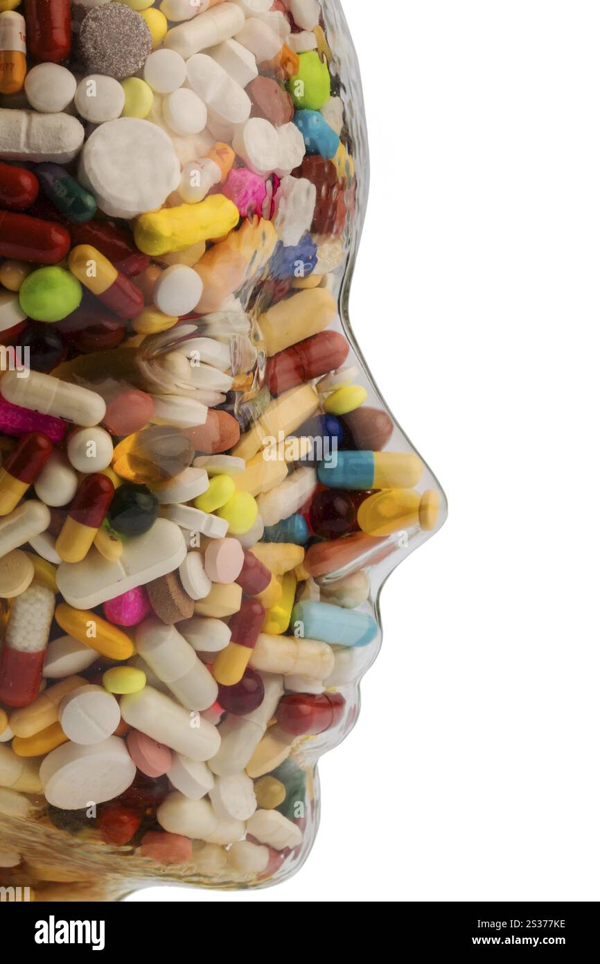 A glass head filled with many tablets. Symbolic photo for medication ...