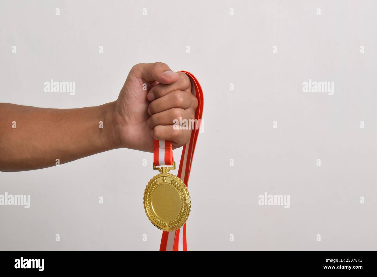 Hand holding gold medal isolated on white background. The winner and ...