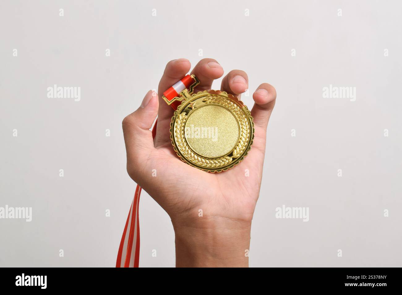 Hand holding gold medal isolated on white background. The winner and ...