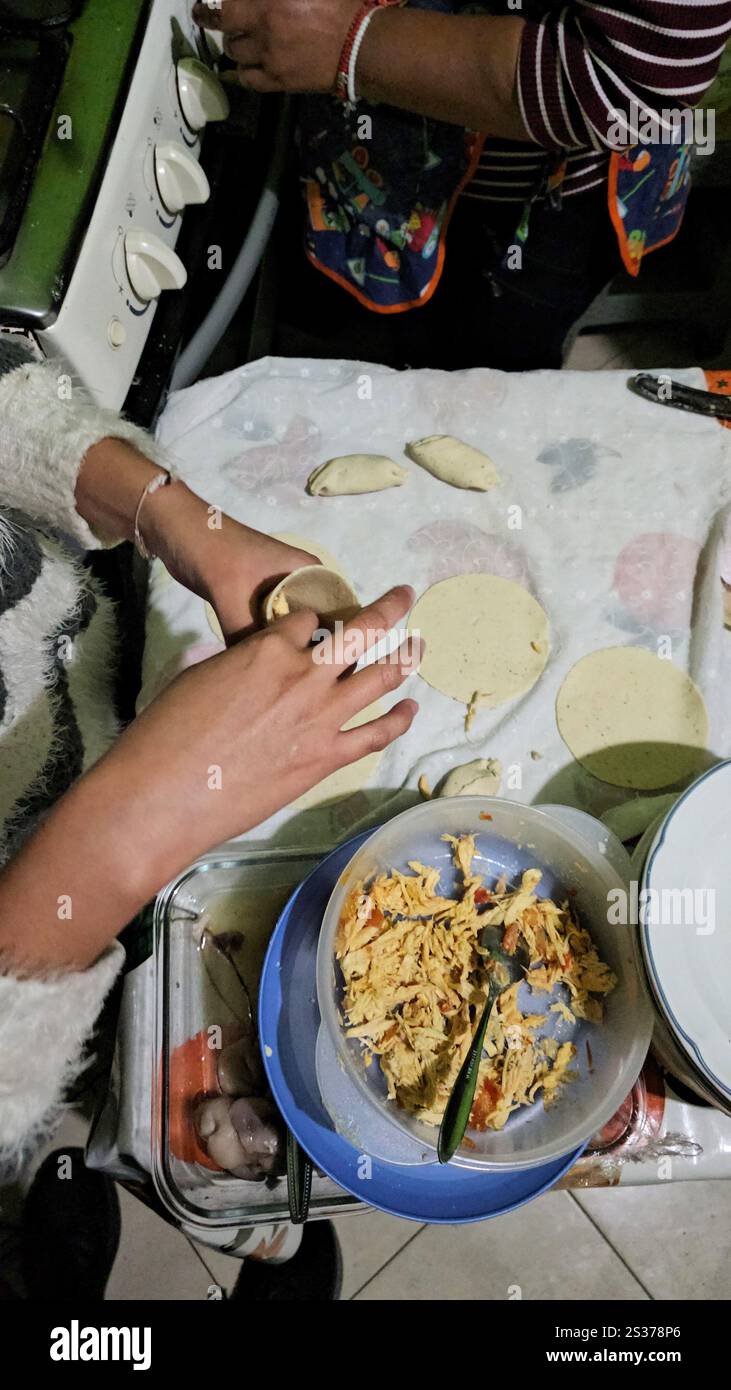 Woman's hands prepare molotes, which is corn dough filled with meat, a ...