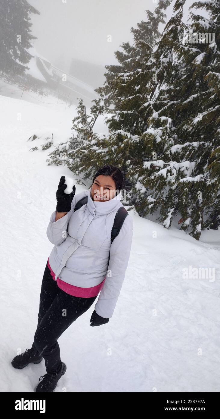 Latin adult woman plays throwing snowballs in the snow due to a cold ...