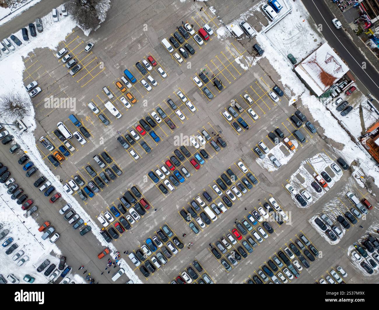 Cars parked in a large lot during winter with snow covering the ground ...