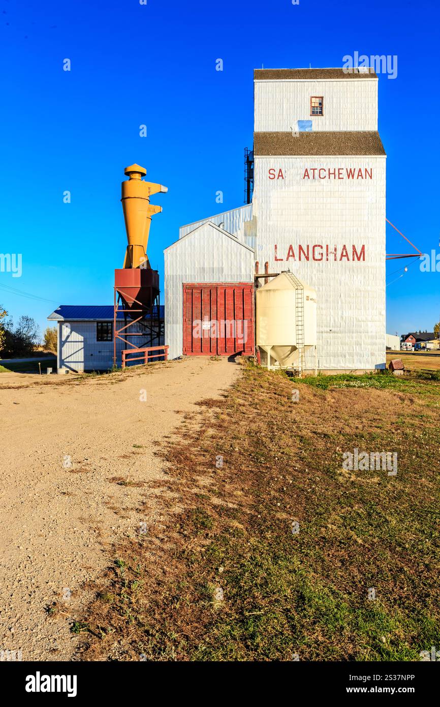 A grain silo with the name Langham on it. The silo is white and red ...