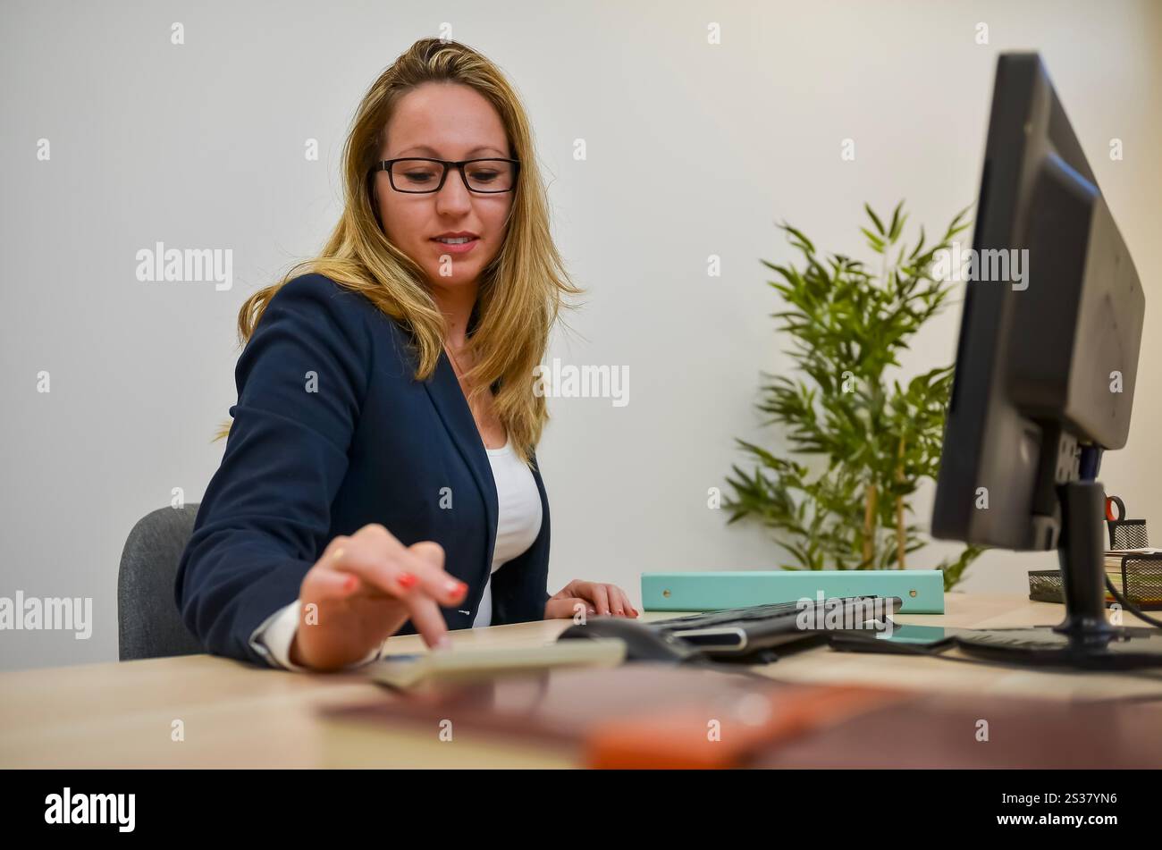 Entrepreneur calculating and working at her computer in a modern office ...