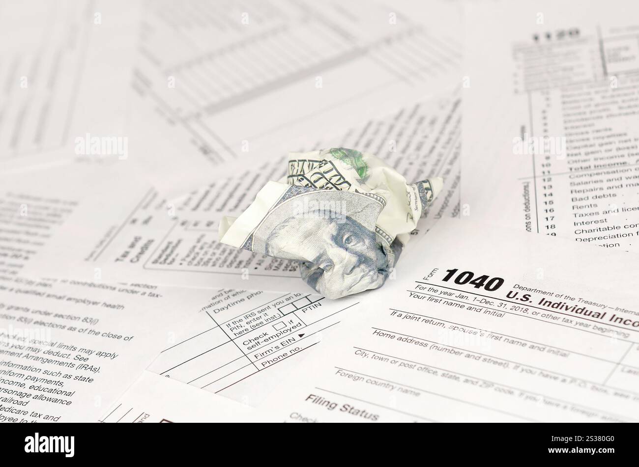 1040 Individual income tax return form and crumpled hundred dollar bill ...