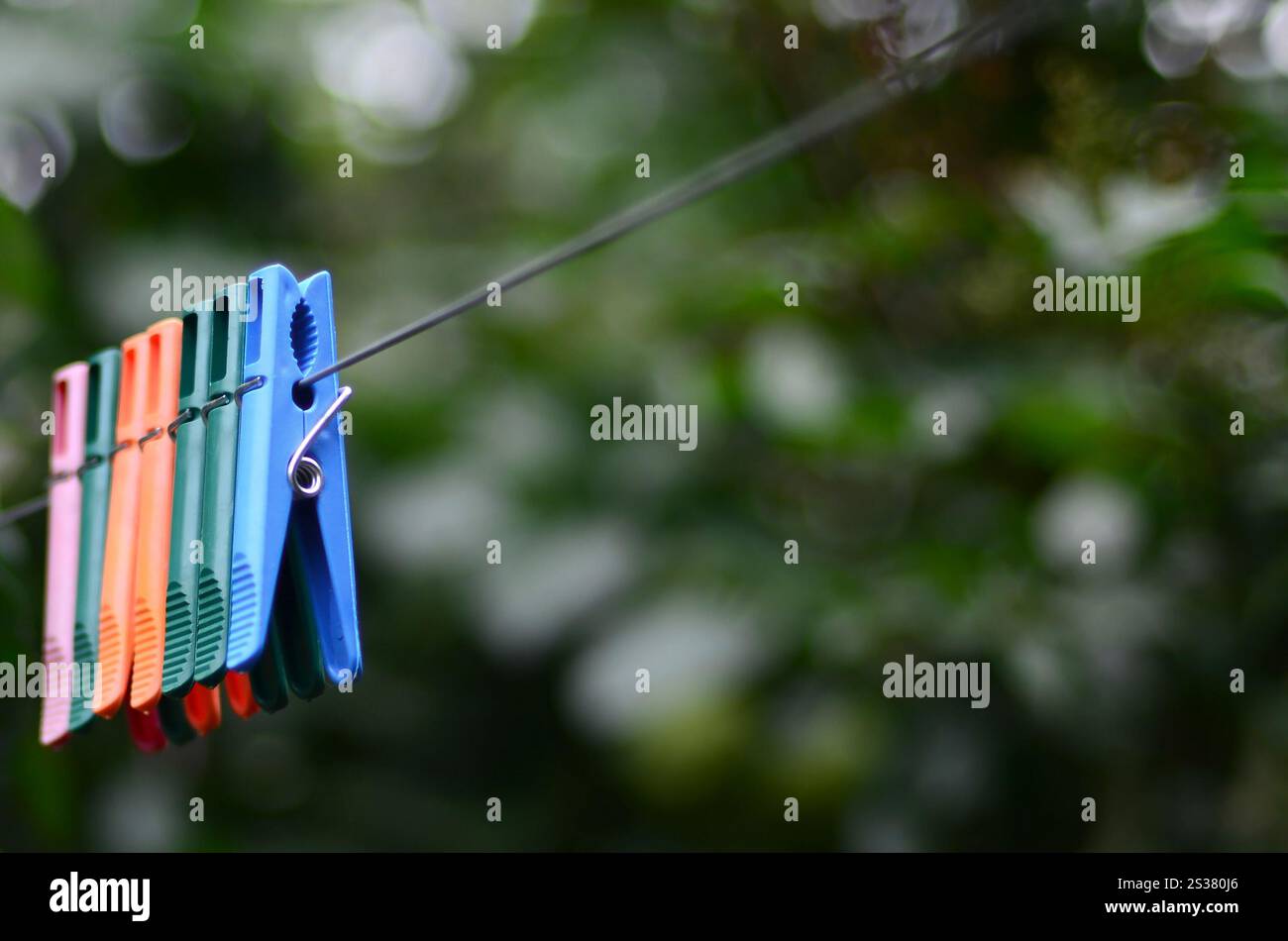Clothespins on a rope hanging outside house, apple tree and blurred ...