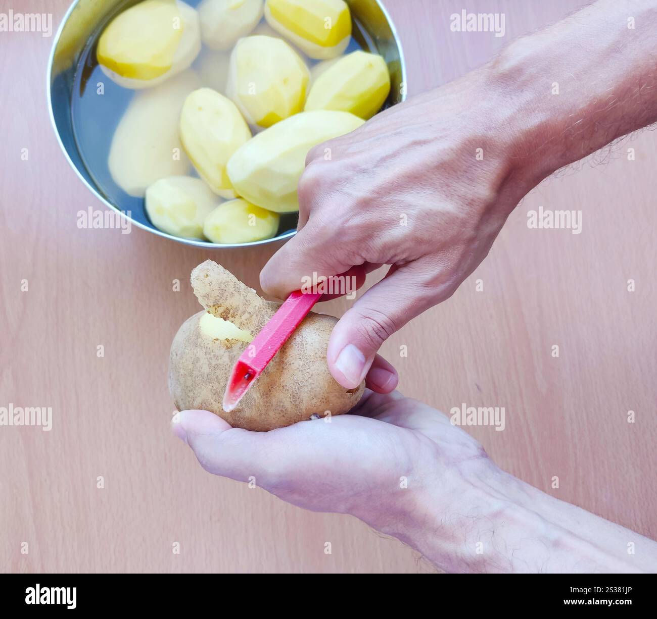 Man holding and peeling potato. Hands cutting potatoes at kitchen to ...
