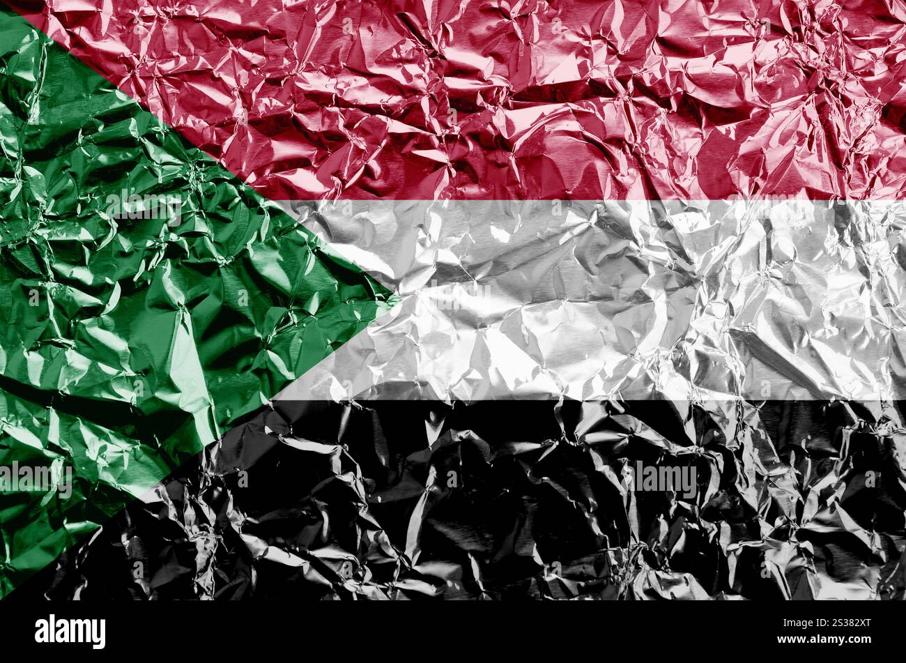Sudan flag depicted in paint colors on shiny crumpled aluminium foil ...