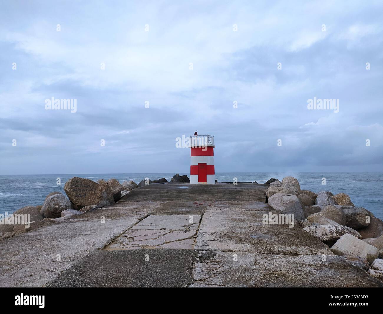 A red and white lighthouse stands proudly atop a sturdy pier ...