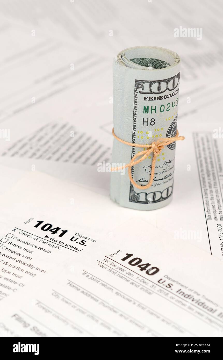 Tax forms lies near roll of hundred dollar bills. Income tax return ...