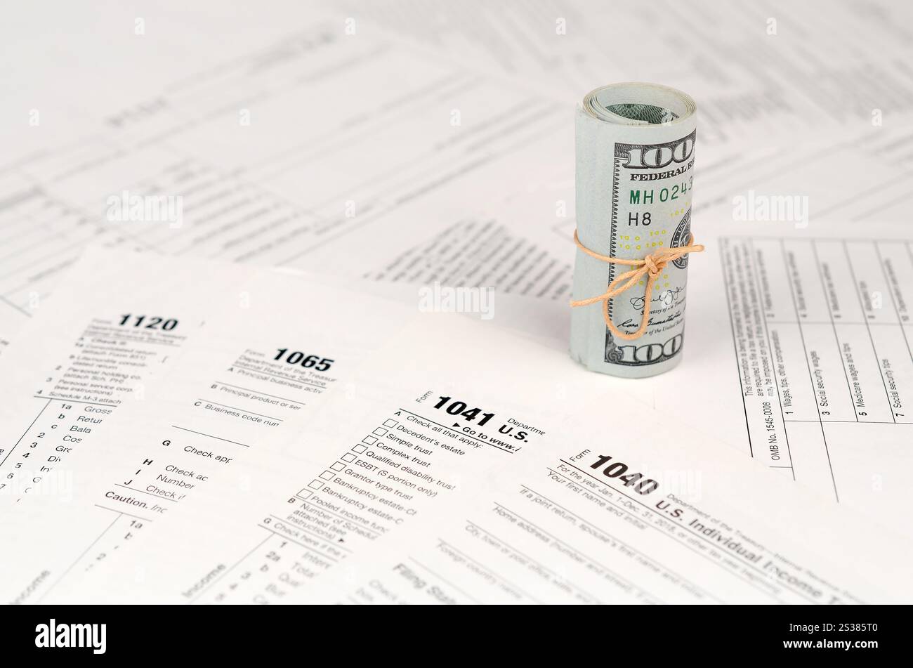 Tax forms lies near roll of hundred dollar bills. Income tax return ...