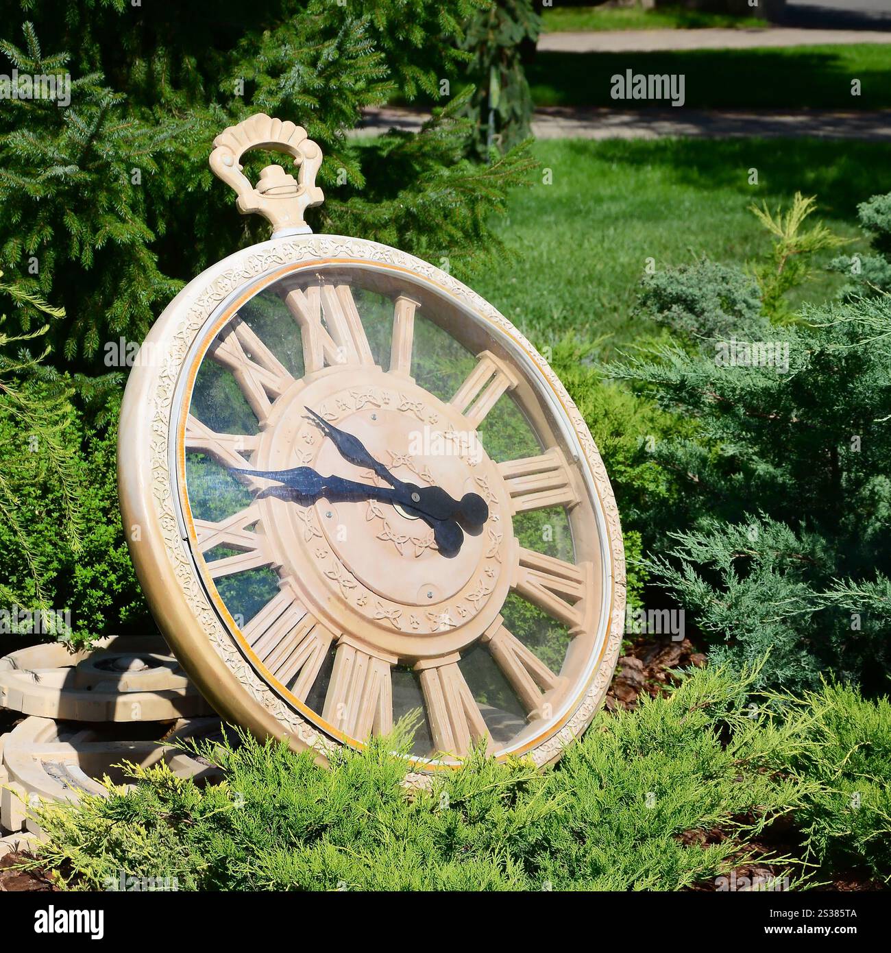 Street clock in a park under branches of trees covered with green ...