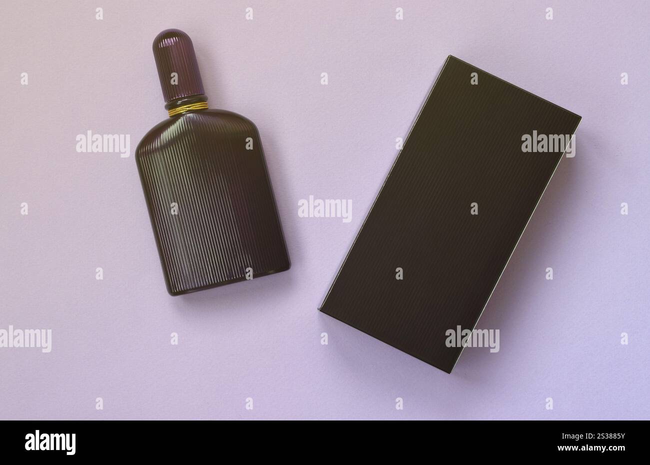 Dark purple perfume bottle with golden ribbon on pastel paper ...