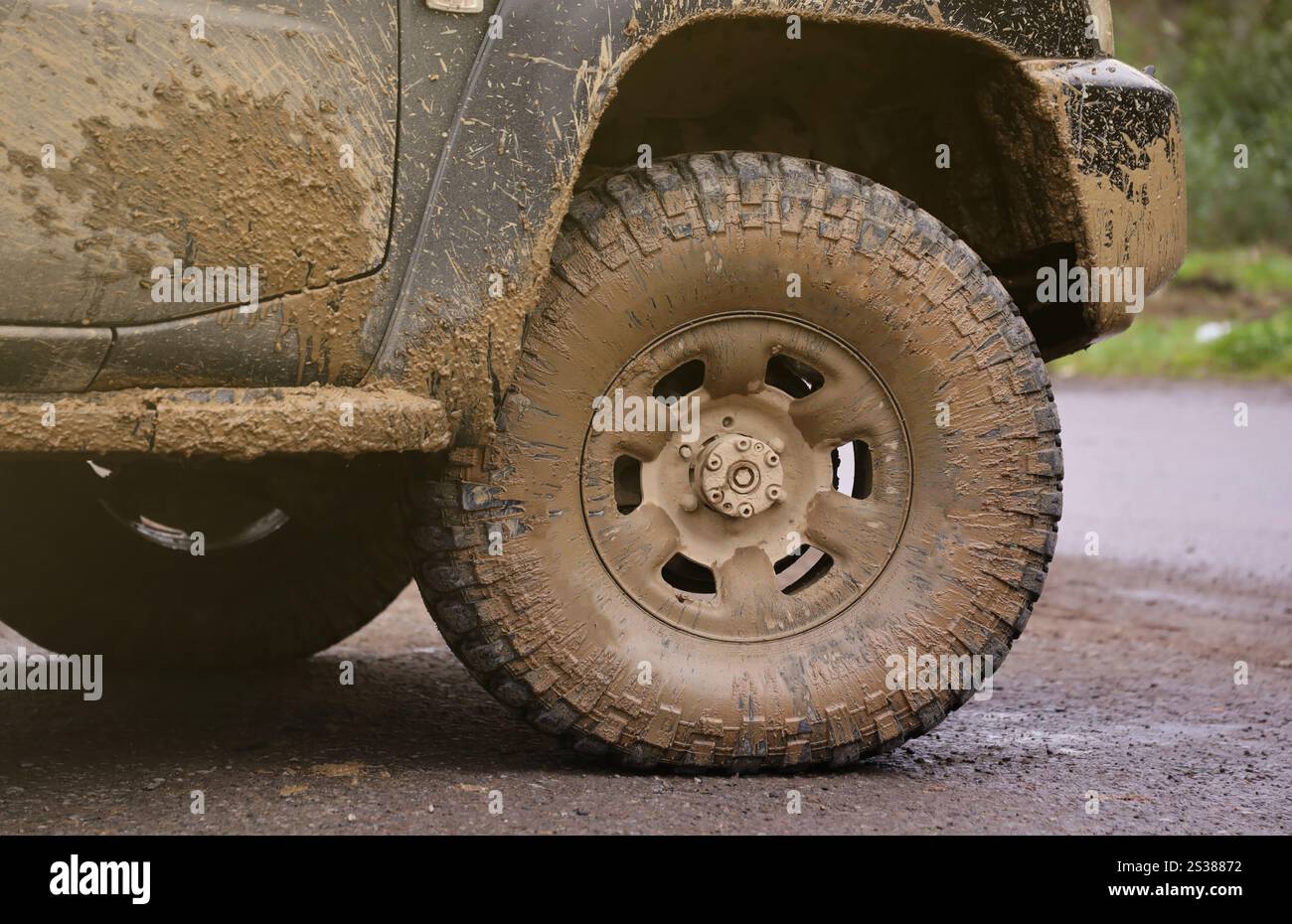 Wheel closeup in a countryside landscape with a mud road. Off-road 4x4 ...