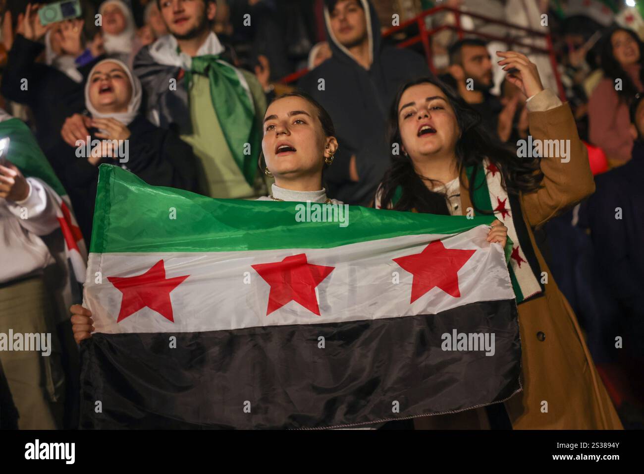 Syrians sing and hold a post-Assad flag during a concert by the ...