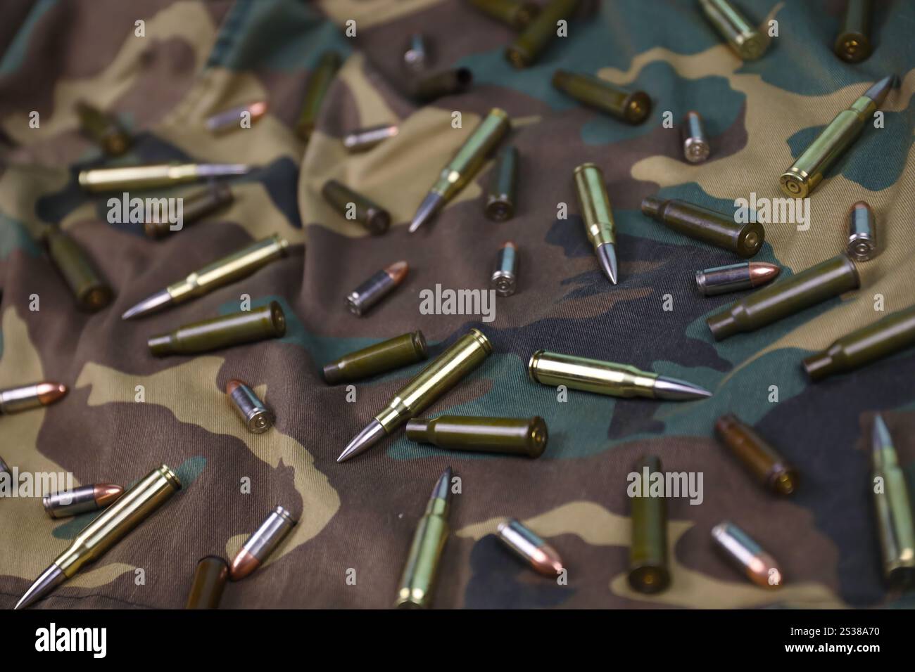 Many rifle bullets and cartridges on dark camouflage background ...