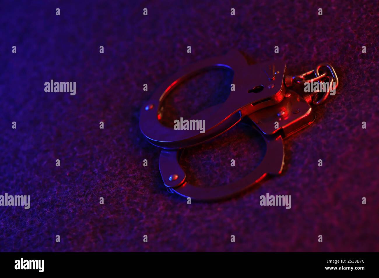 Closed handcuffs on the dark surface at night with police car lights ...