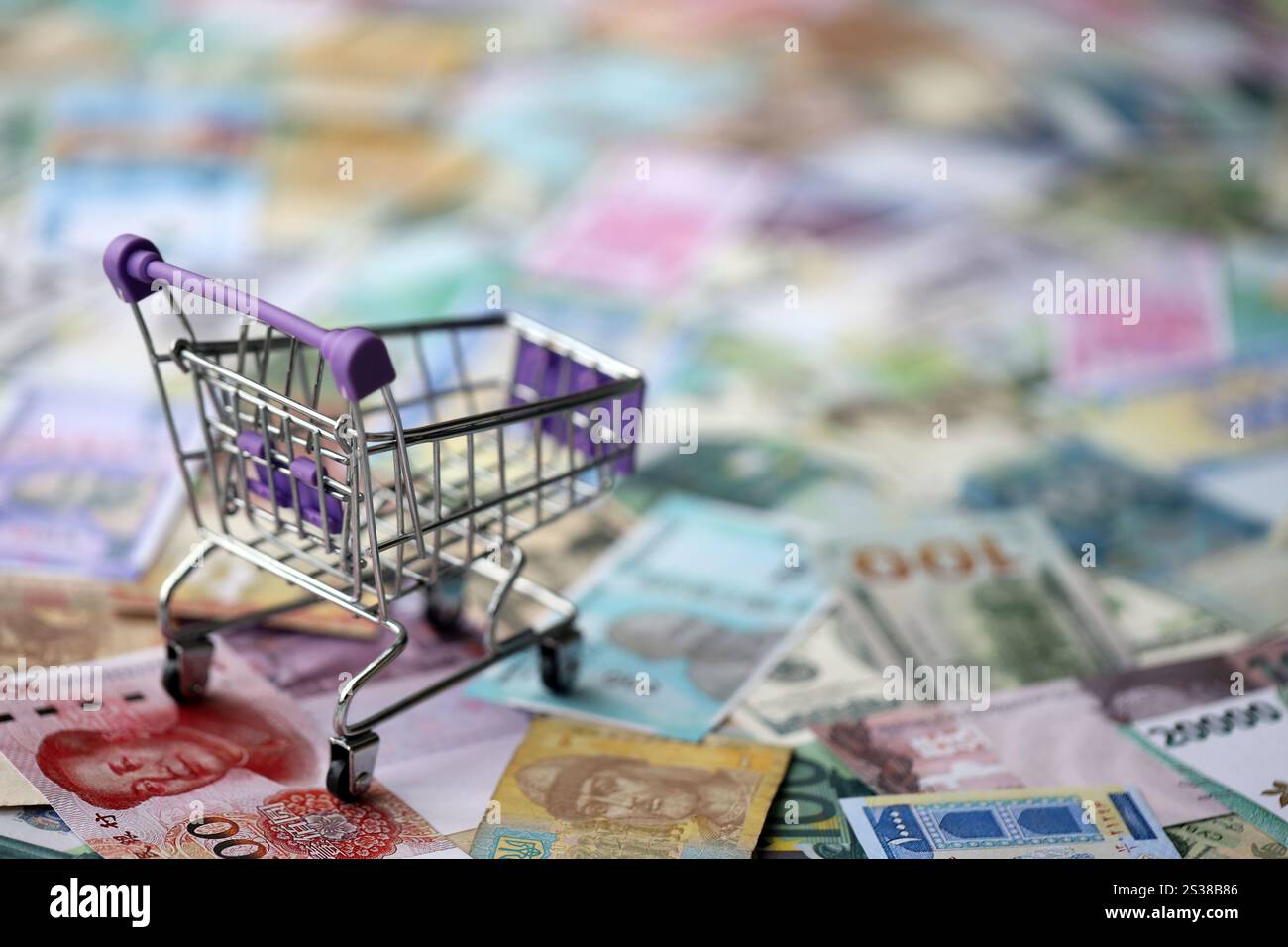 Supermarket trolley on many banknotes of different currency. Background ...
