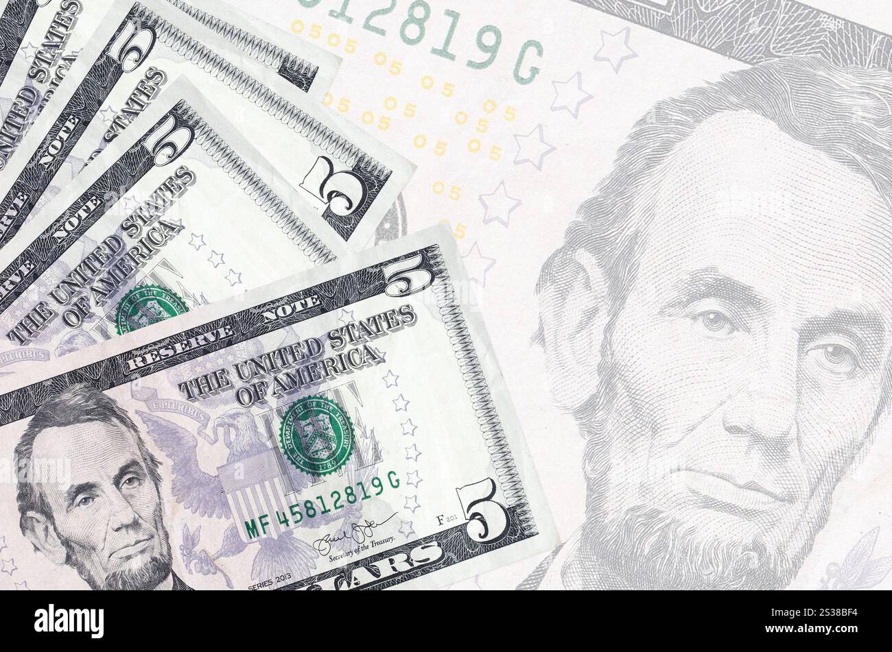 5 US dollars bills lies in stack on background of big semi-transparent ...