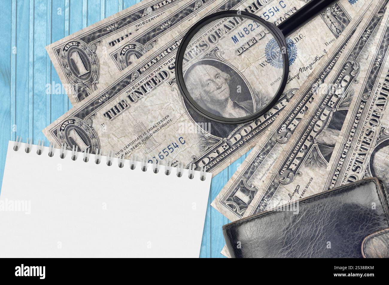 1 US dollar bills and magnifying glass with black purse and notepad ...