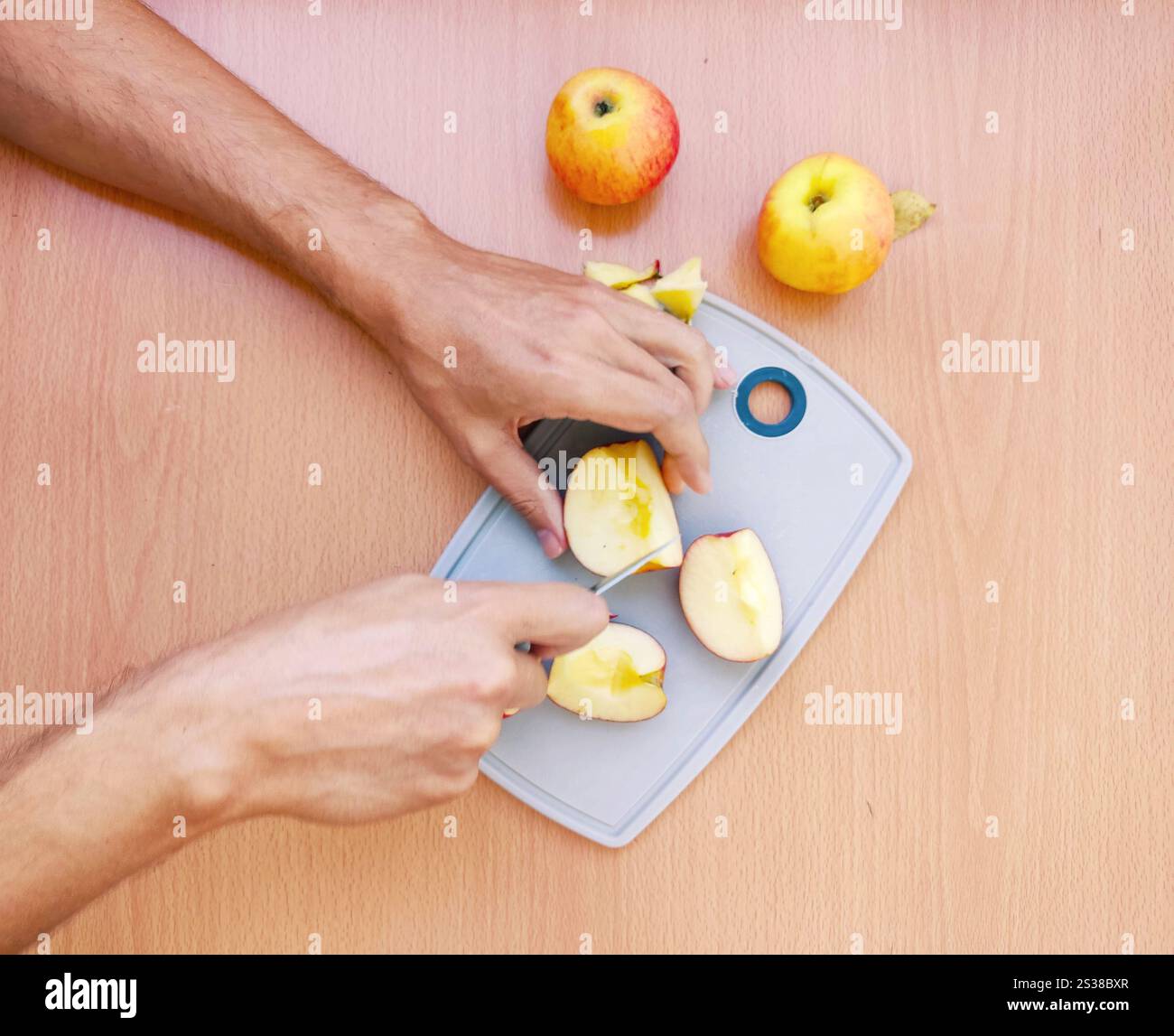 Close up male hands cut an apple into slices. Top view of preparing ...